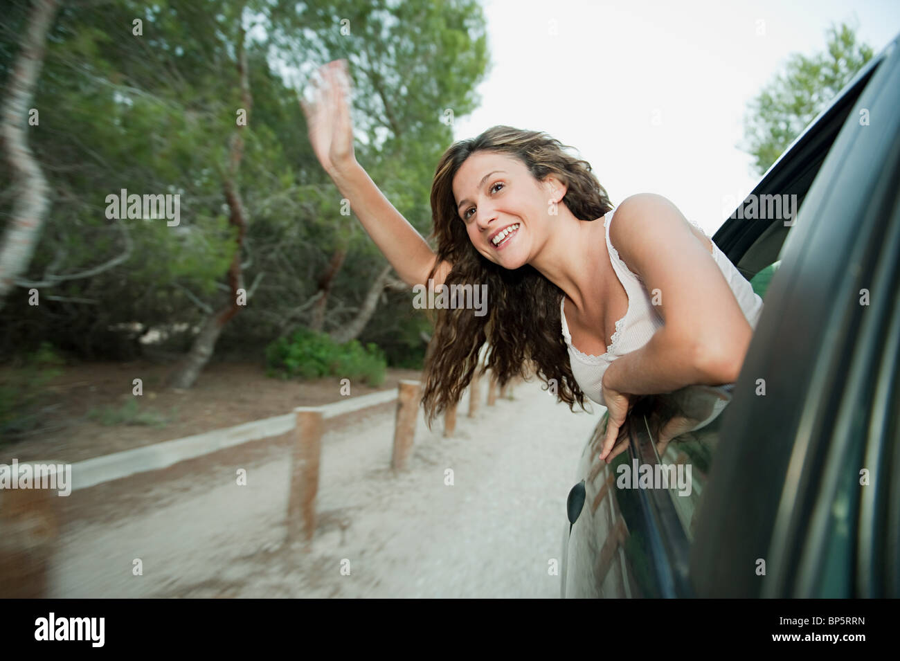 Young woman waving from car window Stock Photo - Alamy
