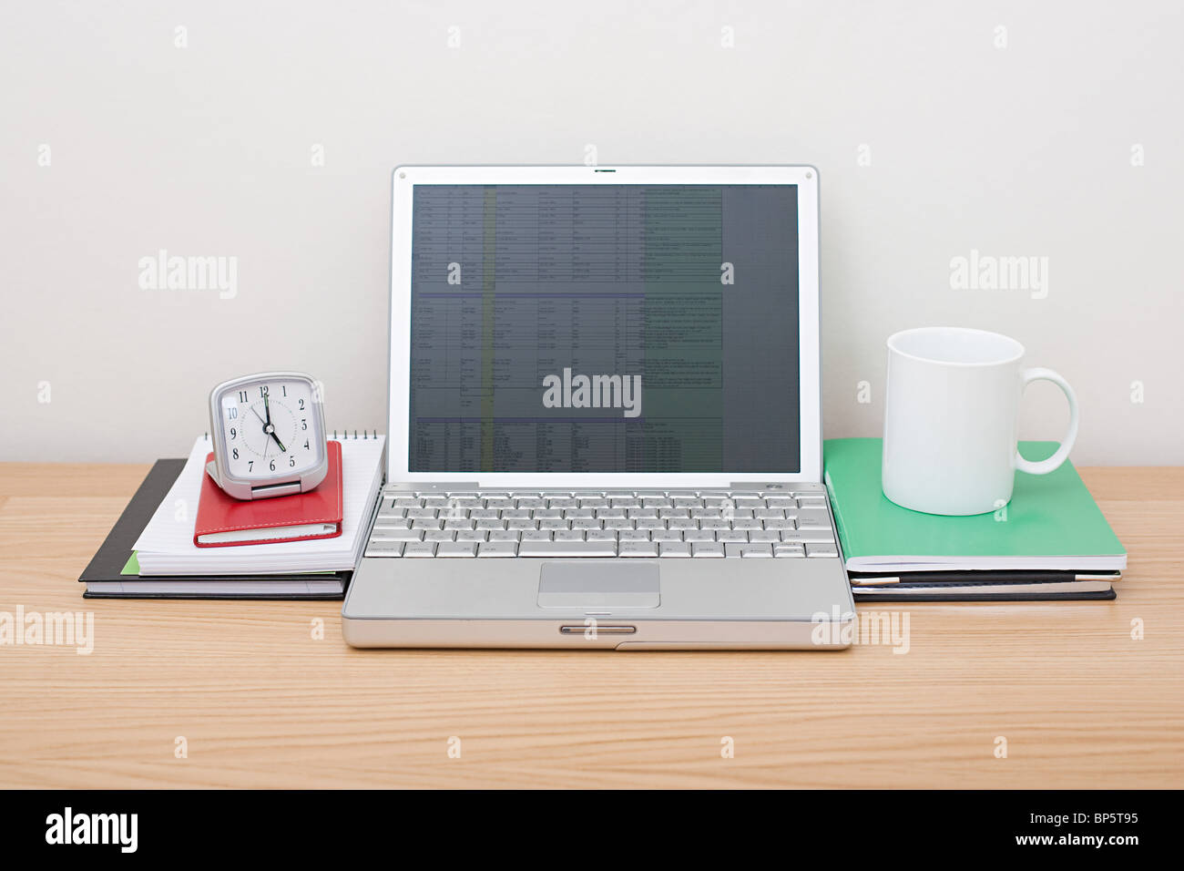 Laptop with alarm clock and mug Stock Photo - Alamy