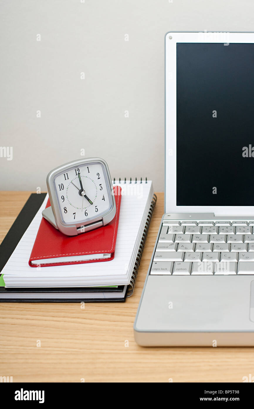 Laptop, notebooks and alarm clock Stock Photo - Alamy
