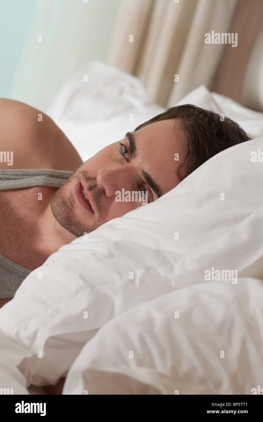 Young man lying in bed Stock Photo - Alamy