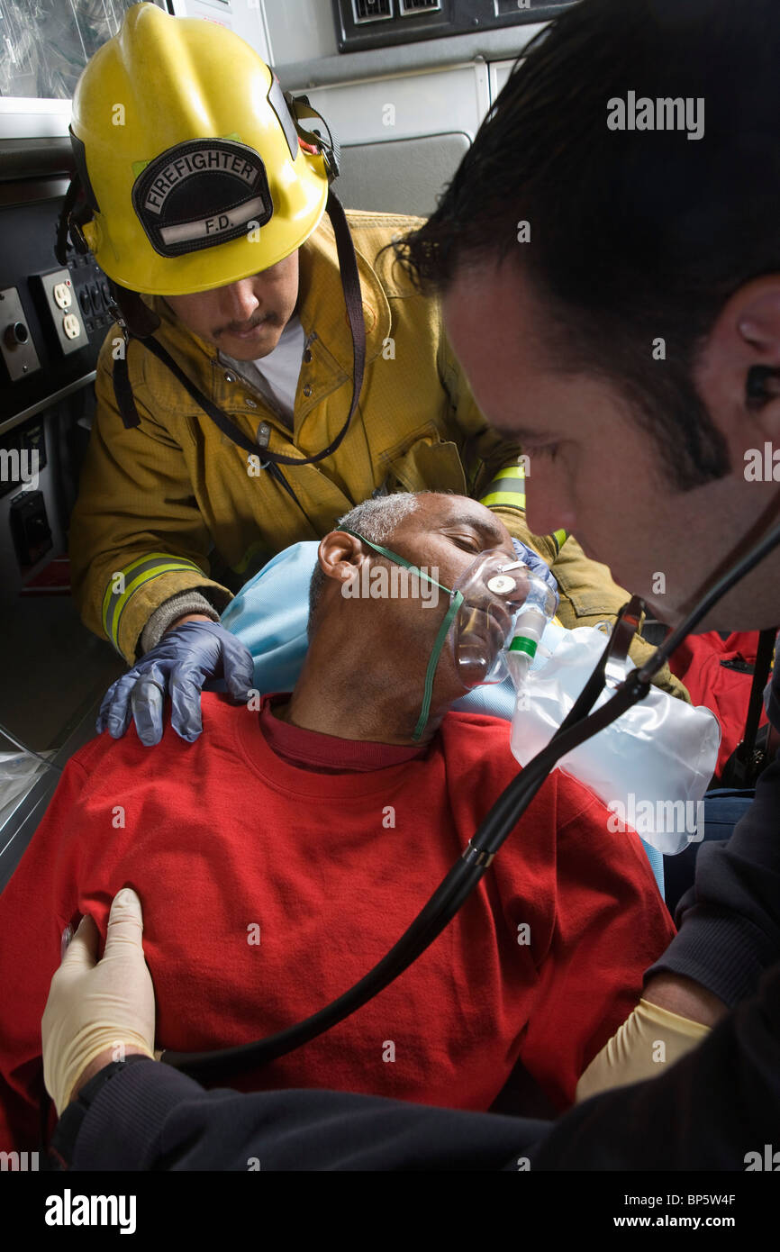 Firefighter and paramedic helping man in ambulance Stock Photo - Alamy