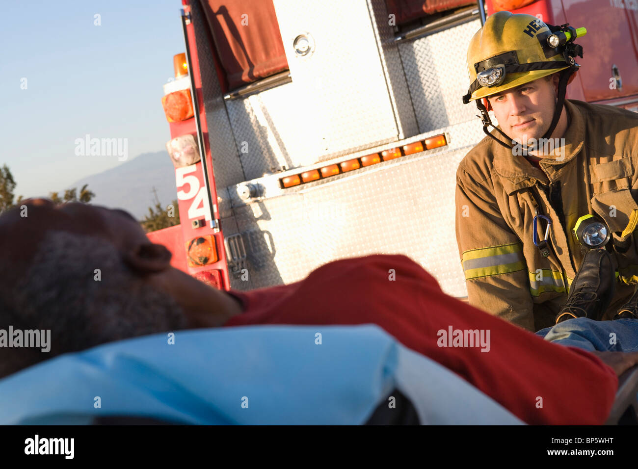 Firefighter with injured person on stretcher Stock Photo - Alamy