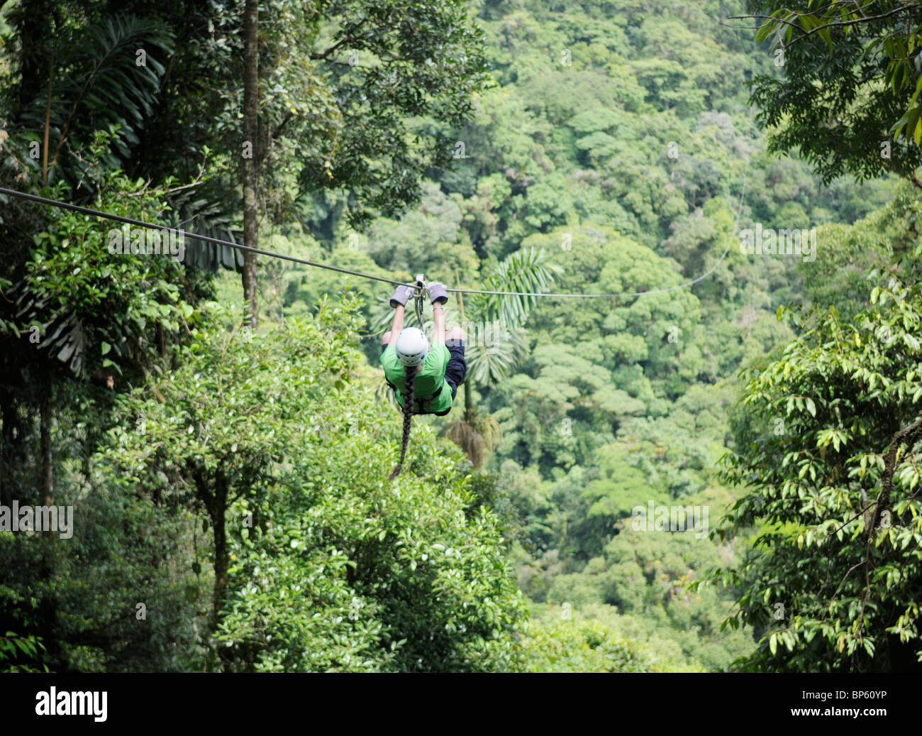 Girl riding a zipline above the rainforest canopy, La Fortuna, Costa ...