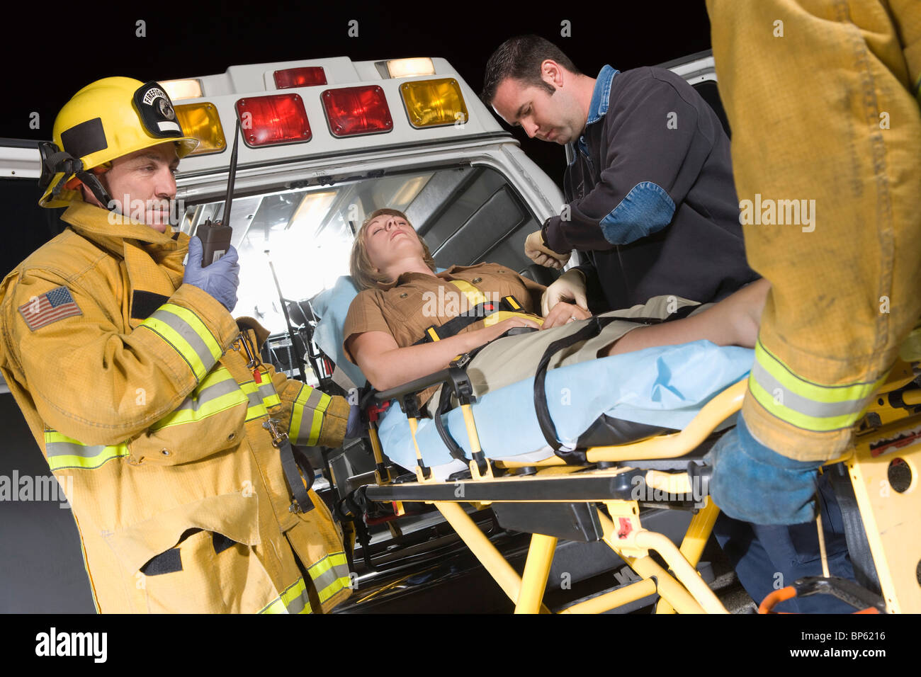 Firefighters and paramedic lifting woman into ambulance Stock Photo - Alamy