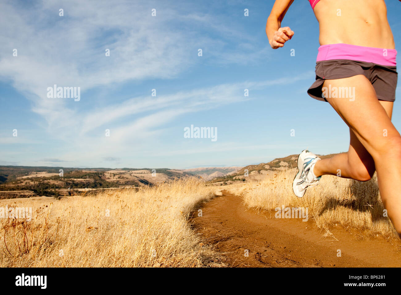 Athletic women trail running through a golden field in Oregon Stock ...