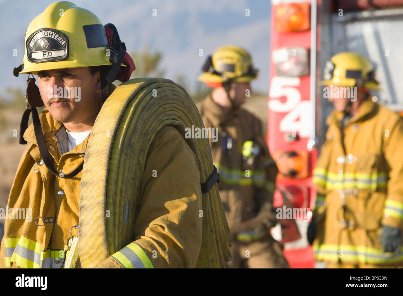 Firefighter carrying hose Stock Photo - Alamy