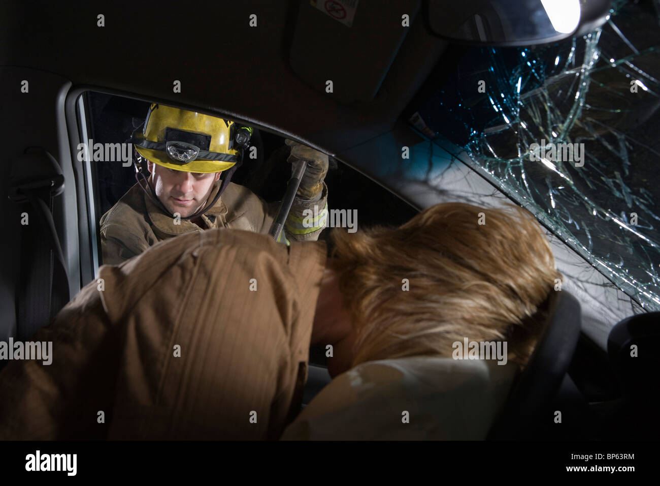 Firefighter rescuing car accident victim Stock Photo - Alamy