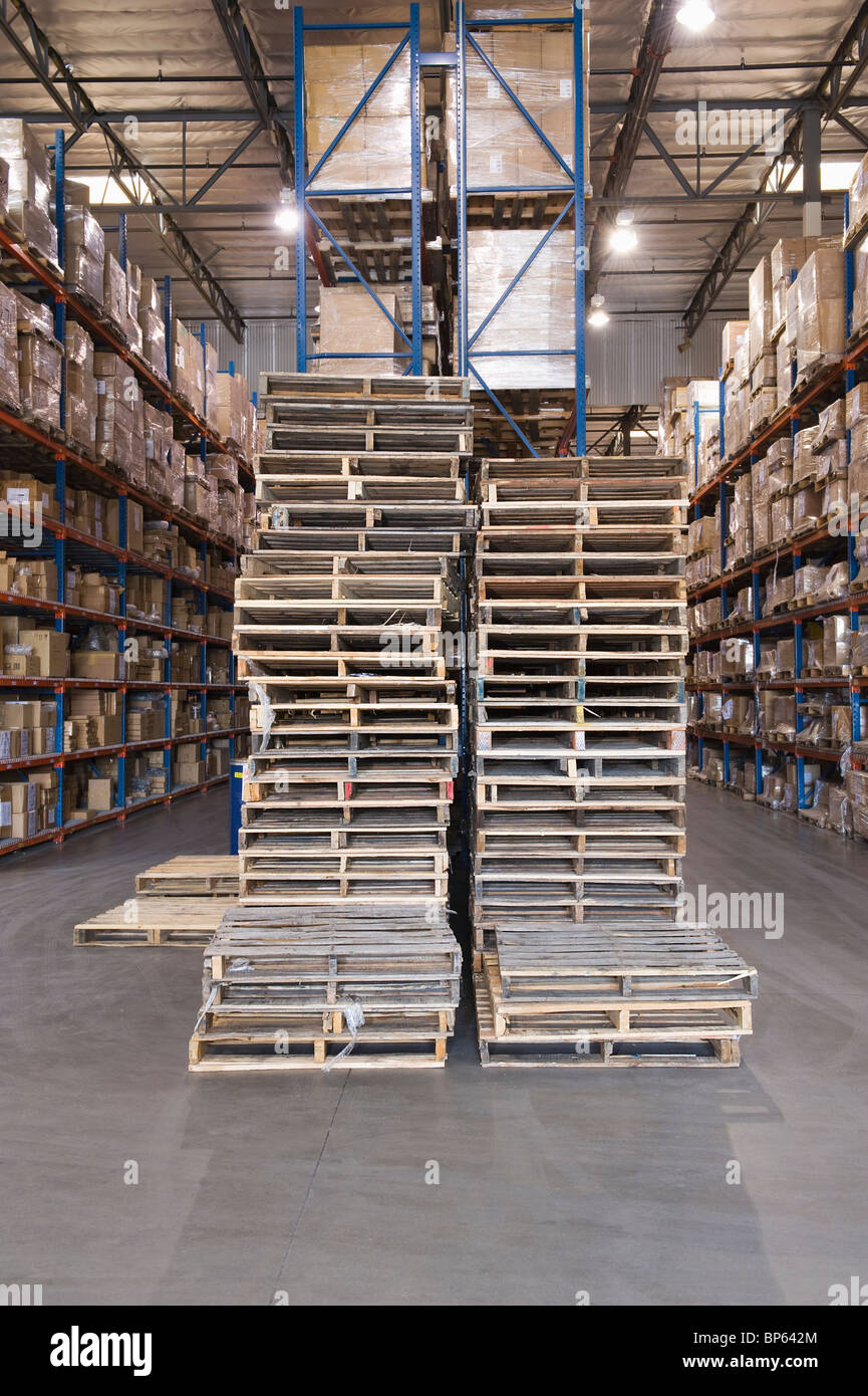 Wooden pallets stacked in distribution warehouse Stock Photo - Alamy