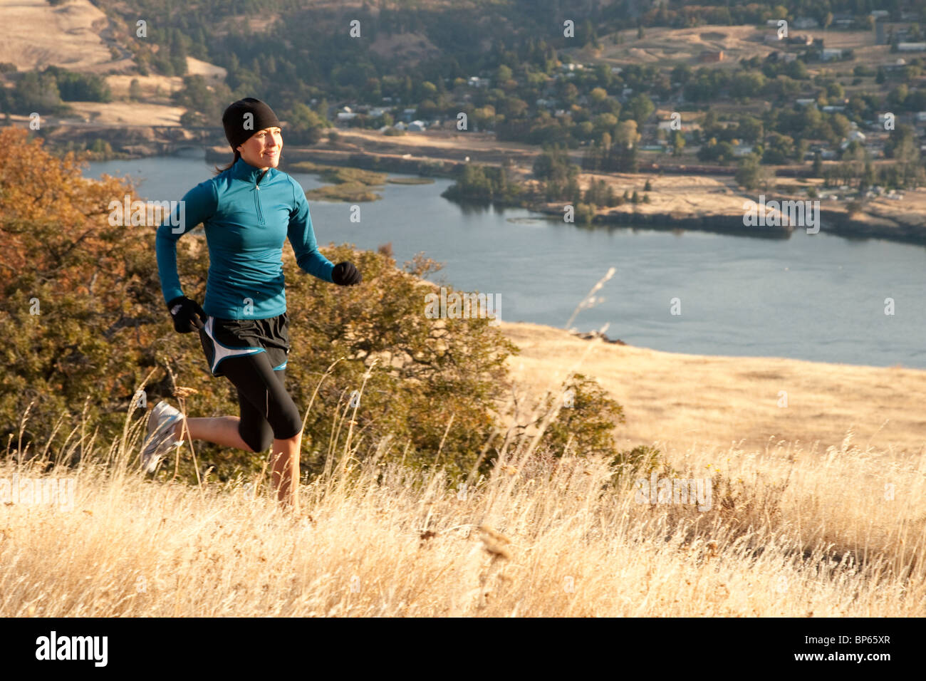 Athletic women trail running through a golden field in Oregon Stock ...