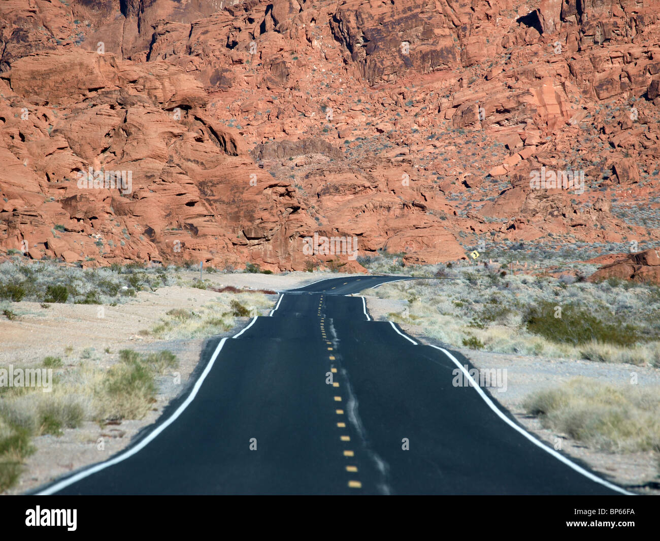 Fresh black pavement leading towards a red sandstone wall in the Nevada ...
