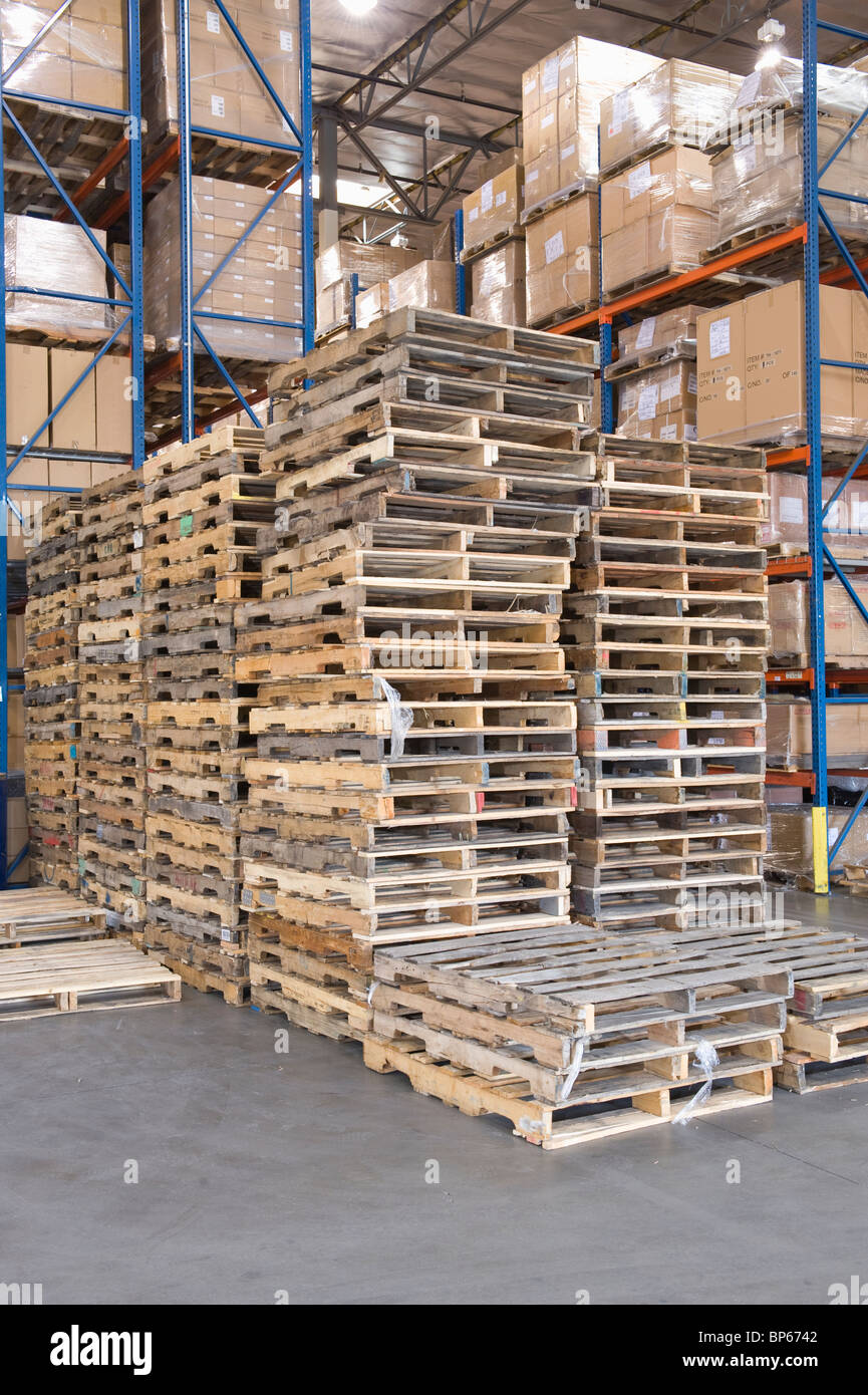 Wooden pallets stacked in distribution warehouse Stock Photo - Alamy