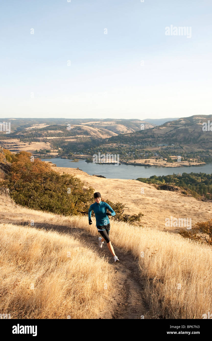 Athletic women trail running through a golden field in Oregon Stock ...