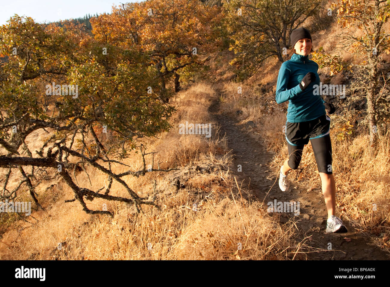 Athletic women trail running through a golden field in Oregon Stock ...