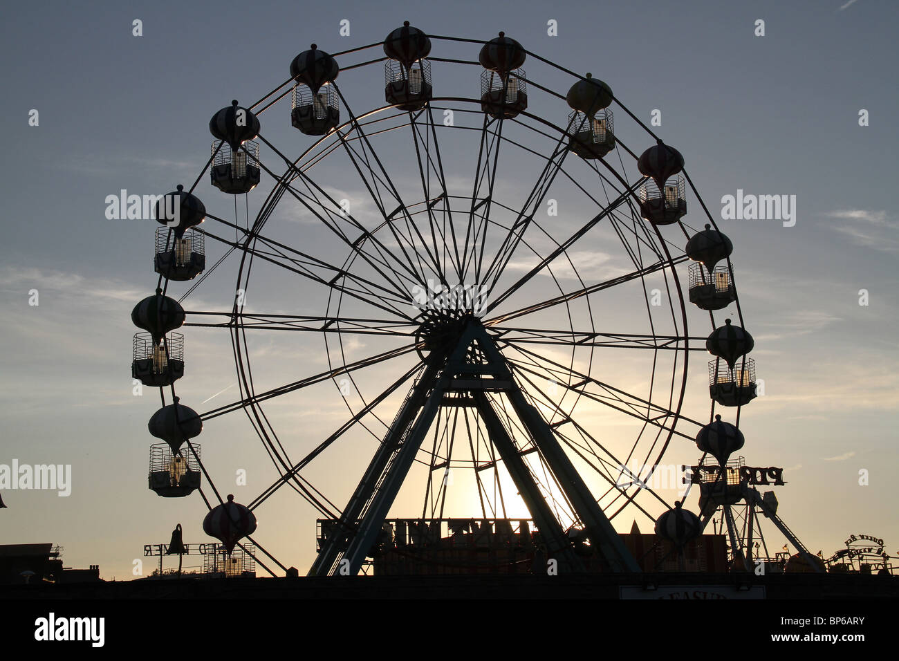 Silhouette of big wheel against late evening sun on the sea front at ...