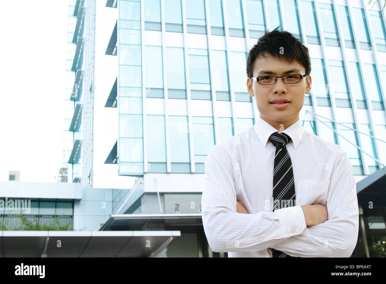 An Asian business executive standing in front of an office building ...