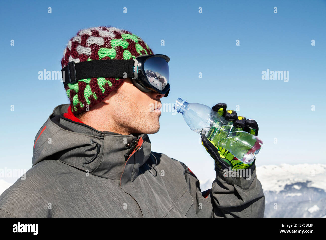 Young man in ski wear drinking water from a bottle, profile Stock Photo ...