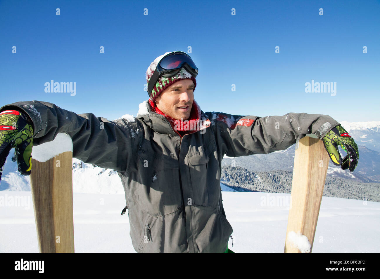 Young man leaning on skis Stock Photo - Alamy