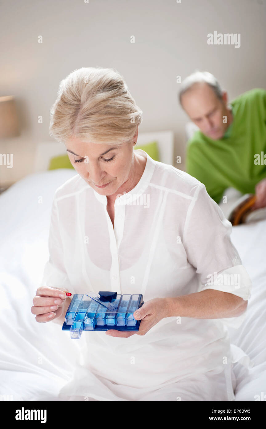 Woman taking a capsule with her husband behind her Stock Photo - Alamy