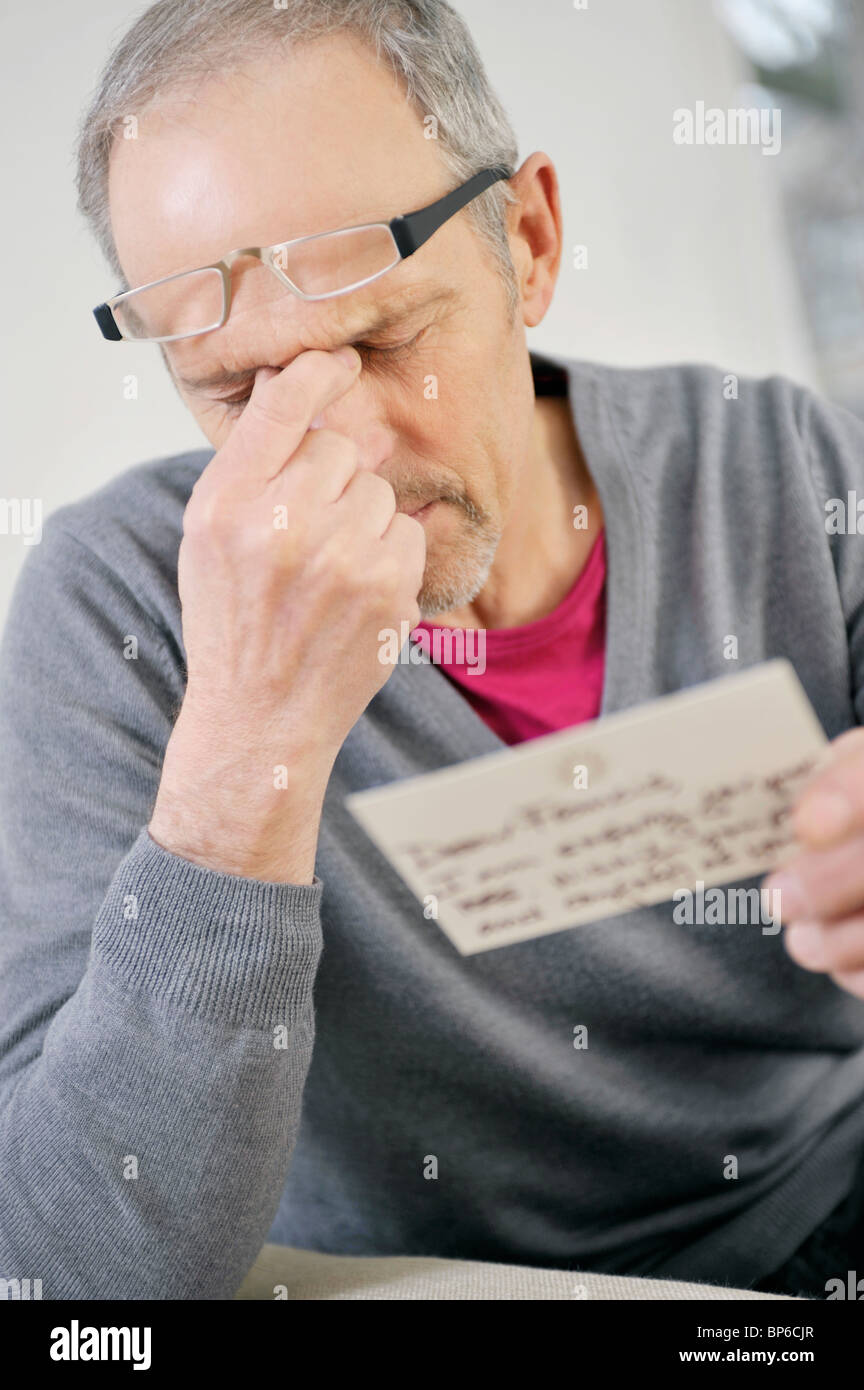 Man looking serious while reading a postcard Stock Photo - Alamy