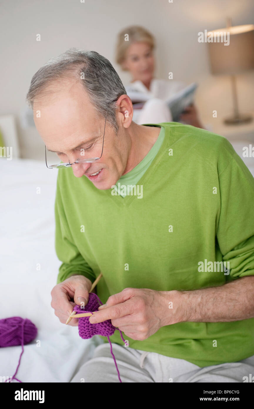 Man knitting with a woman in the background Stock Photo - Alamy