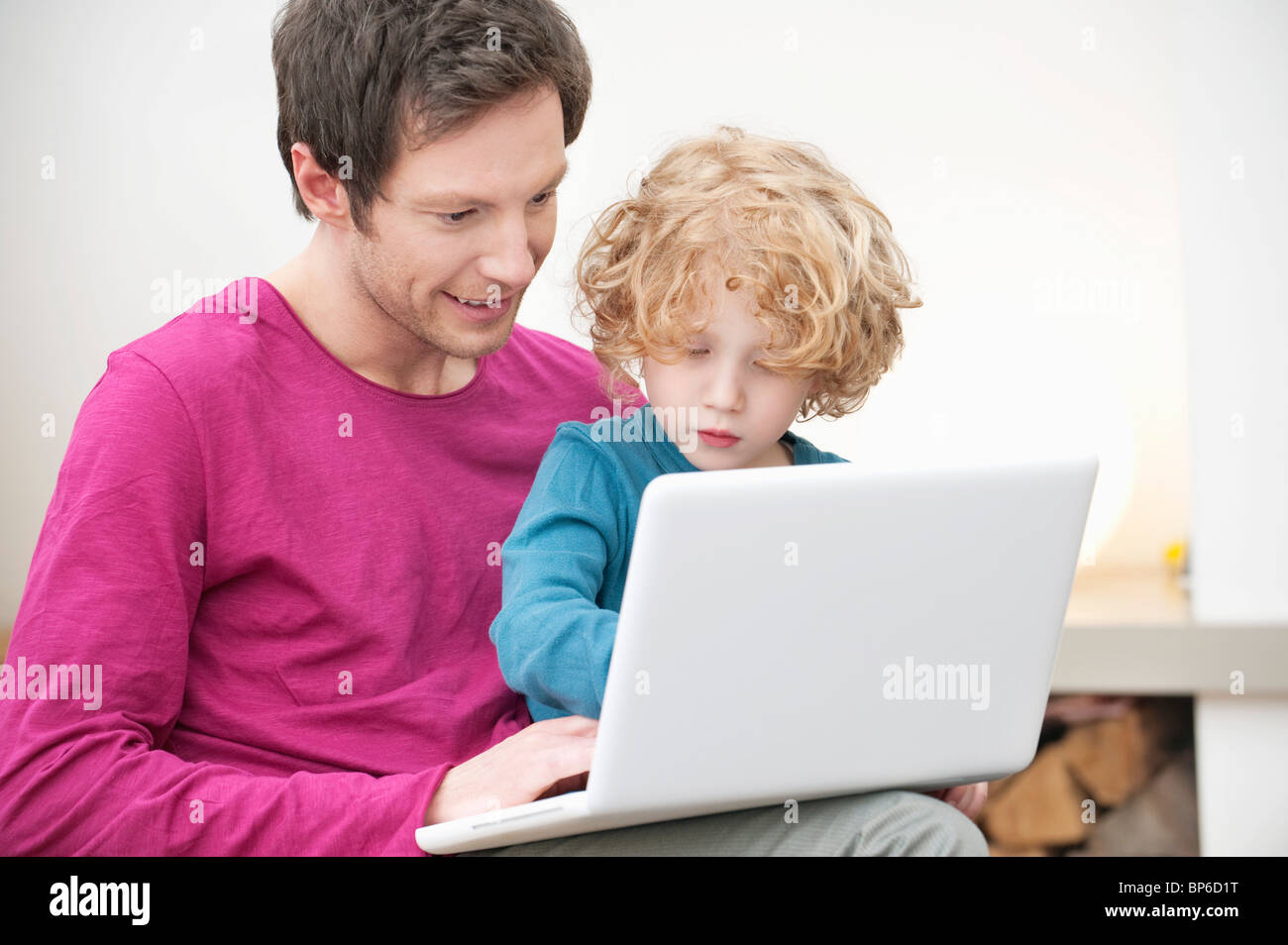 Close-up of a man assisting his son in using a laptop Stock Photo - Alamy