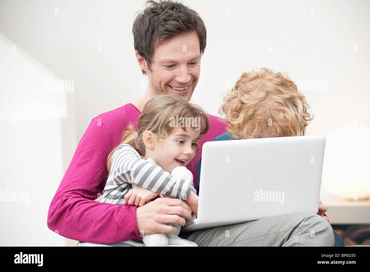 Close-up of a man assisting his son and daughter in using a laptop Stock Photo - Alamy