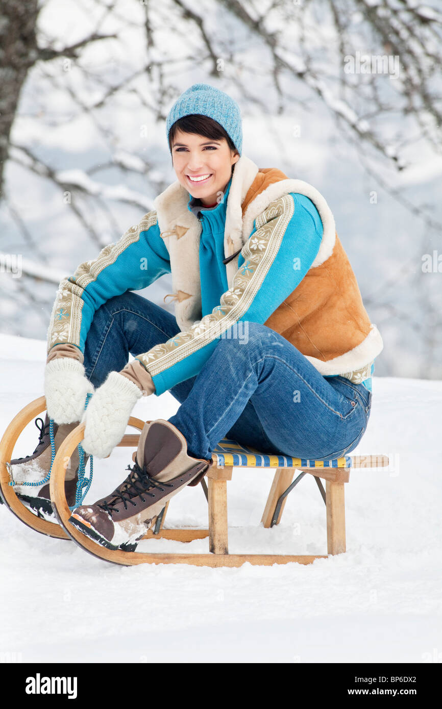Young woman sitting on sled Stock Photo - Alamy