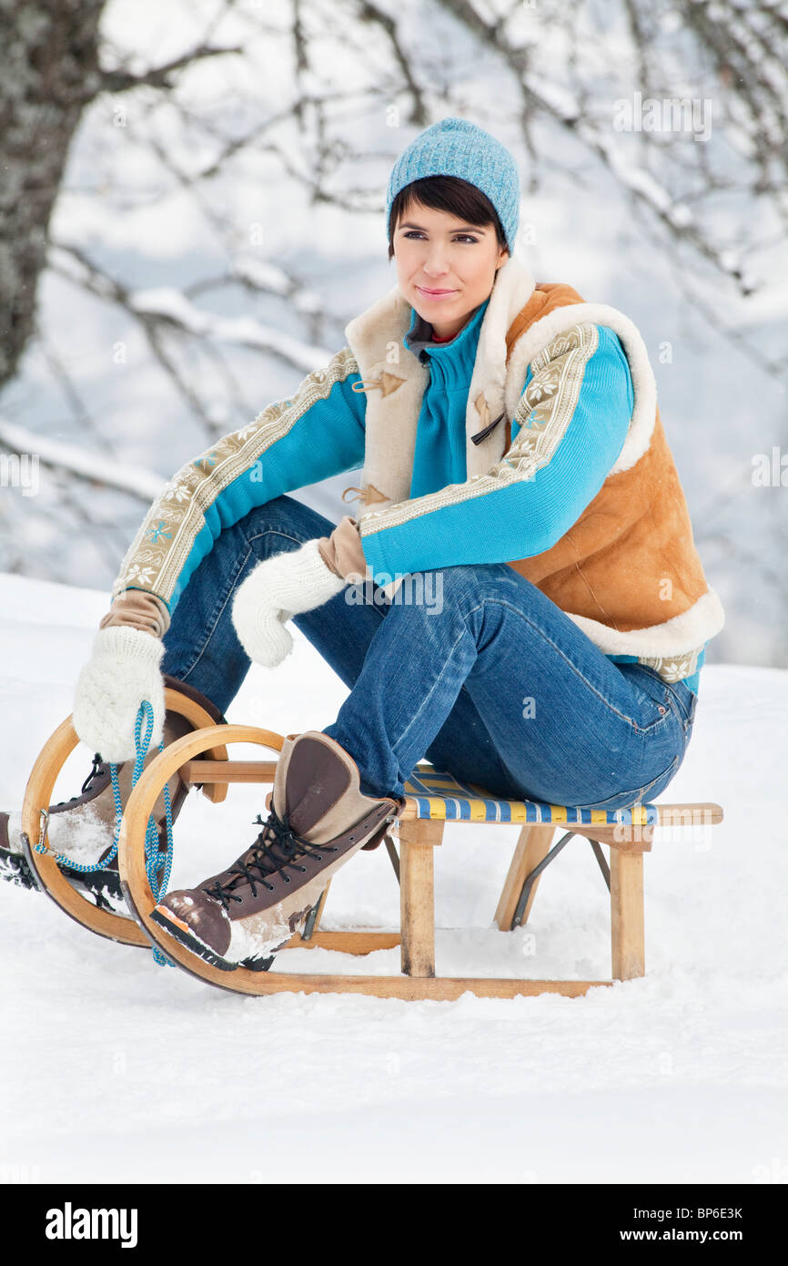 Young woman sitting on sled Stock Photo - Alamy