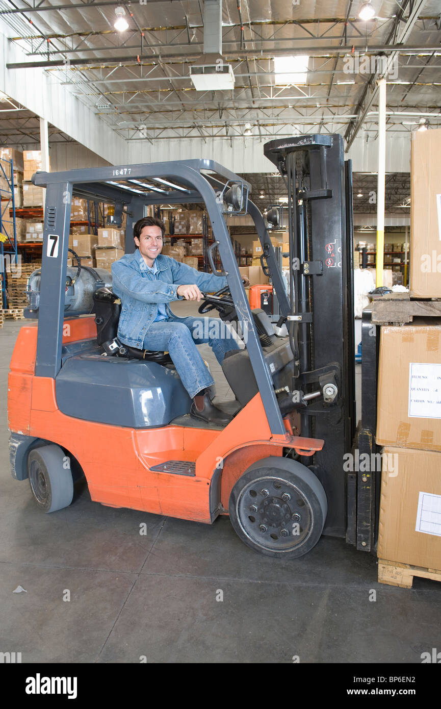 Man operating fork lift truck in distribution warehouse Stock Photo - Alamy
