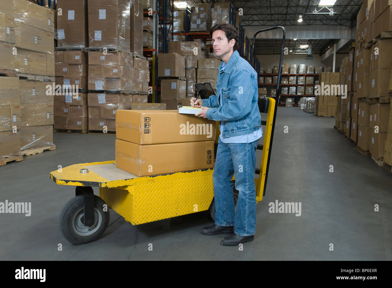 Man operating trolley in distribution warehouse Stock Photo - Alamy