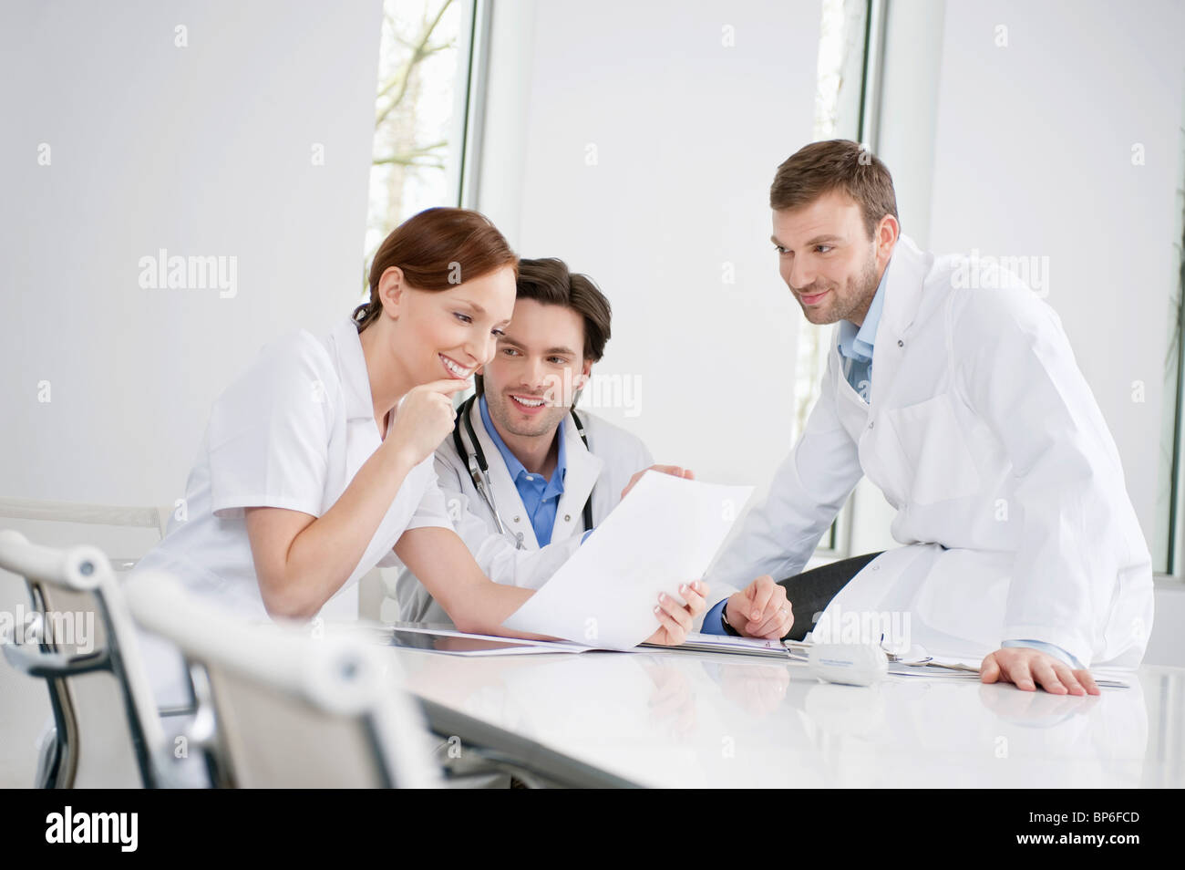 Three doctors examining a medical report Stock Photo - Alamy