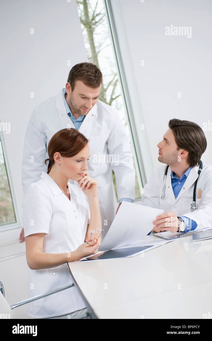 Three doctors examining a medical report Stock Photo - Alamy