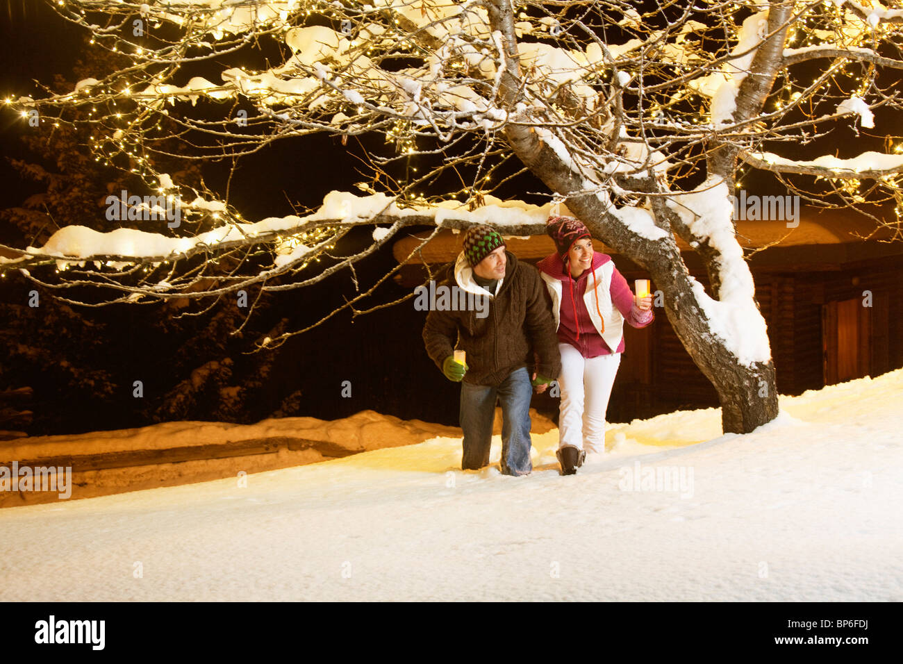 Young couple holding candles, walking in snow by night Stock Photo - Alamy