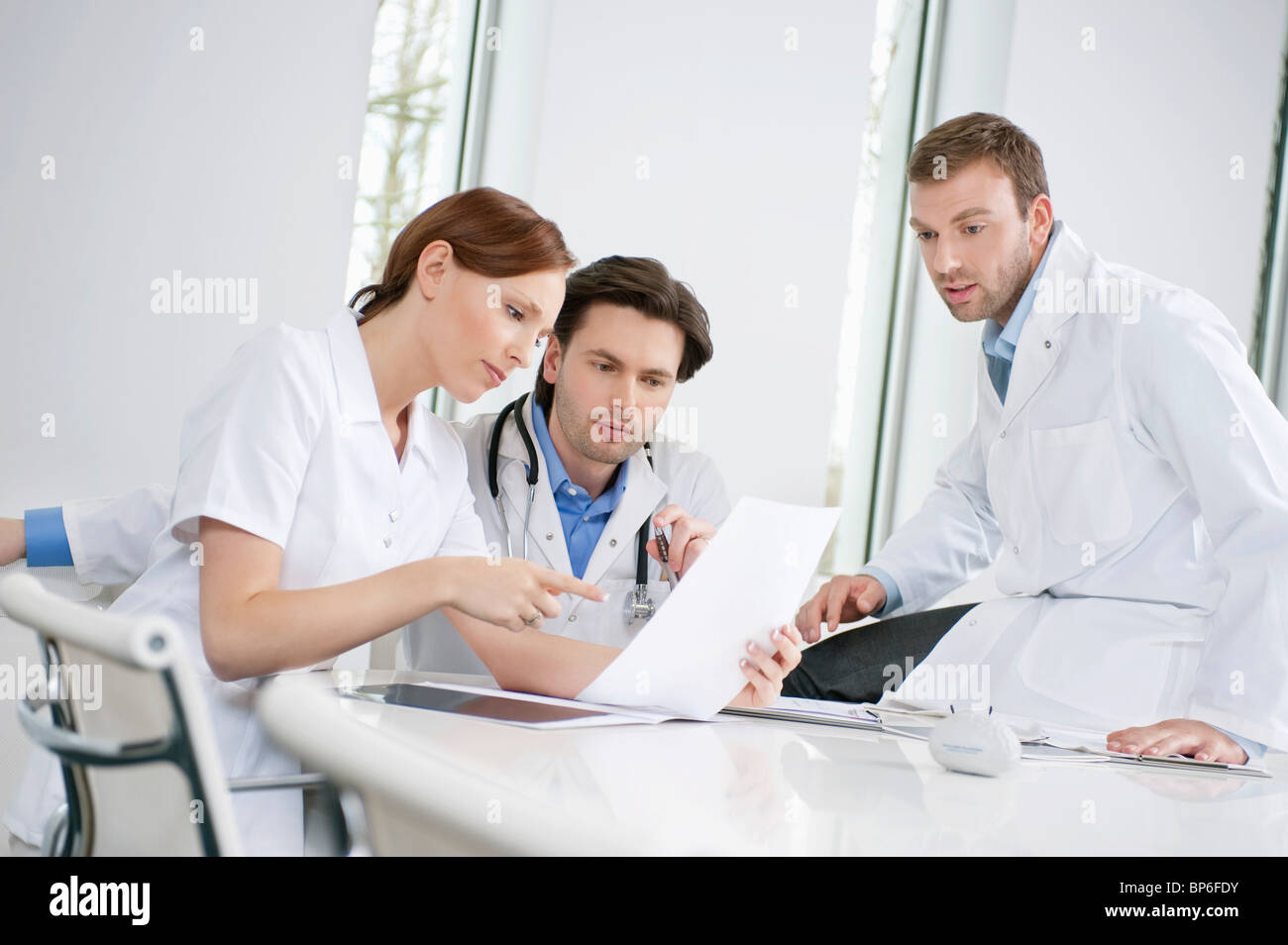 Three doctors examining a medical report Stock Photo - Alamy
