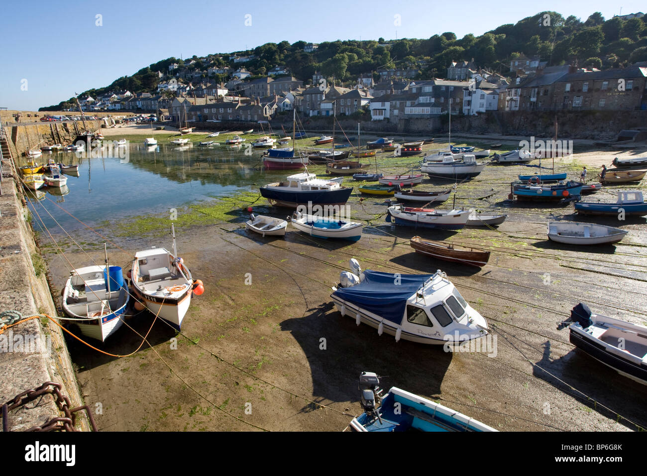 Boats left dry by the receding tide in Mousehole Harbour, Cornwall ...