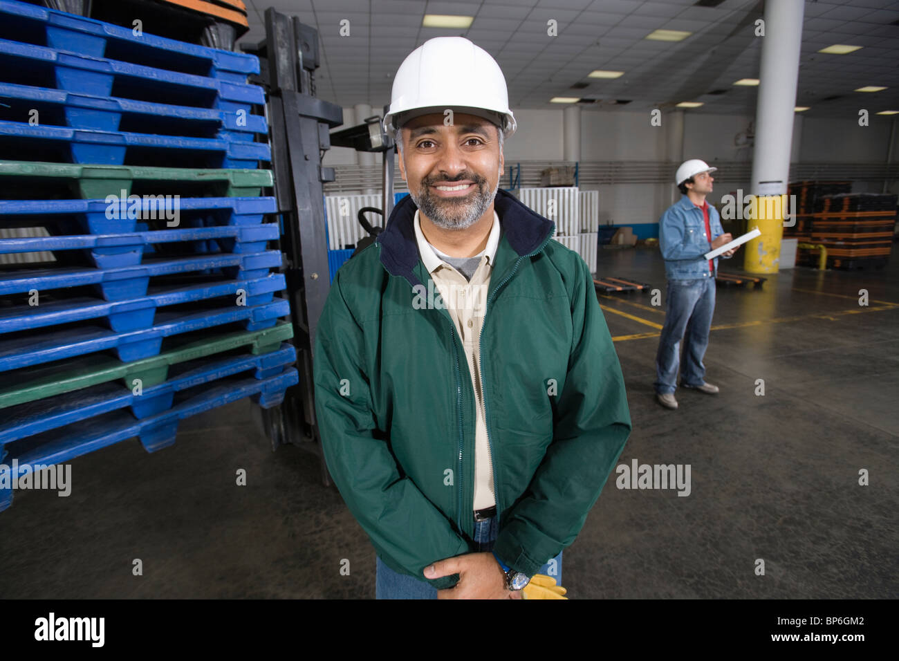 Cheerful man standing in factory, wearing hart hat Stock Photo - Alamy