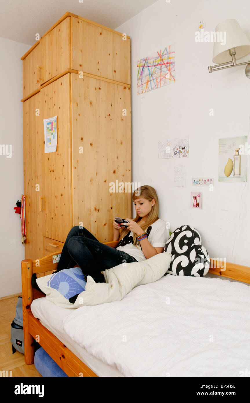 grumpy teenager girl sitting on her bed a playing with a playstation ...