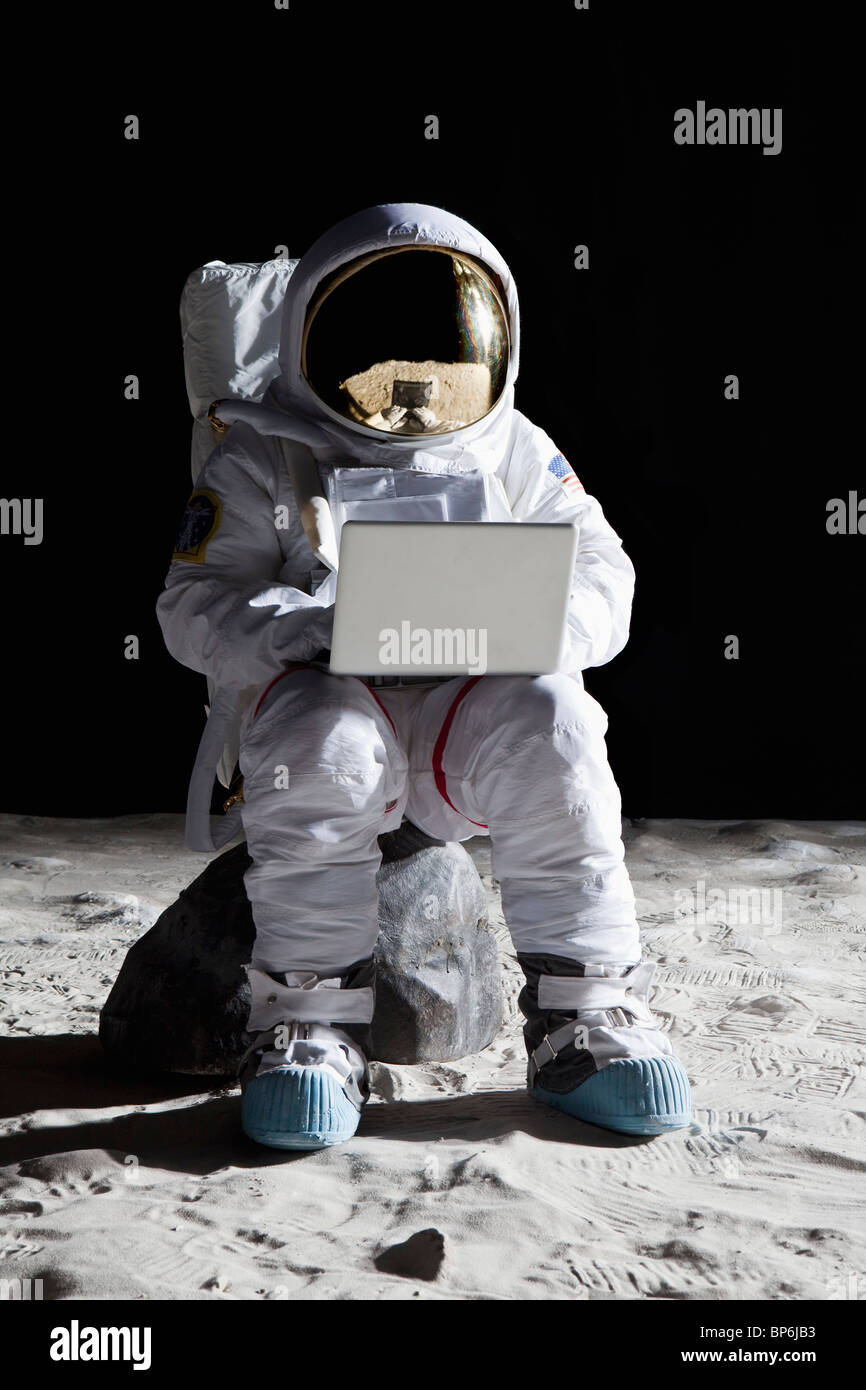 An astronaut on the moon sitting on a rock using a laptop Stock Photo ...