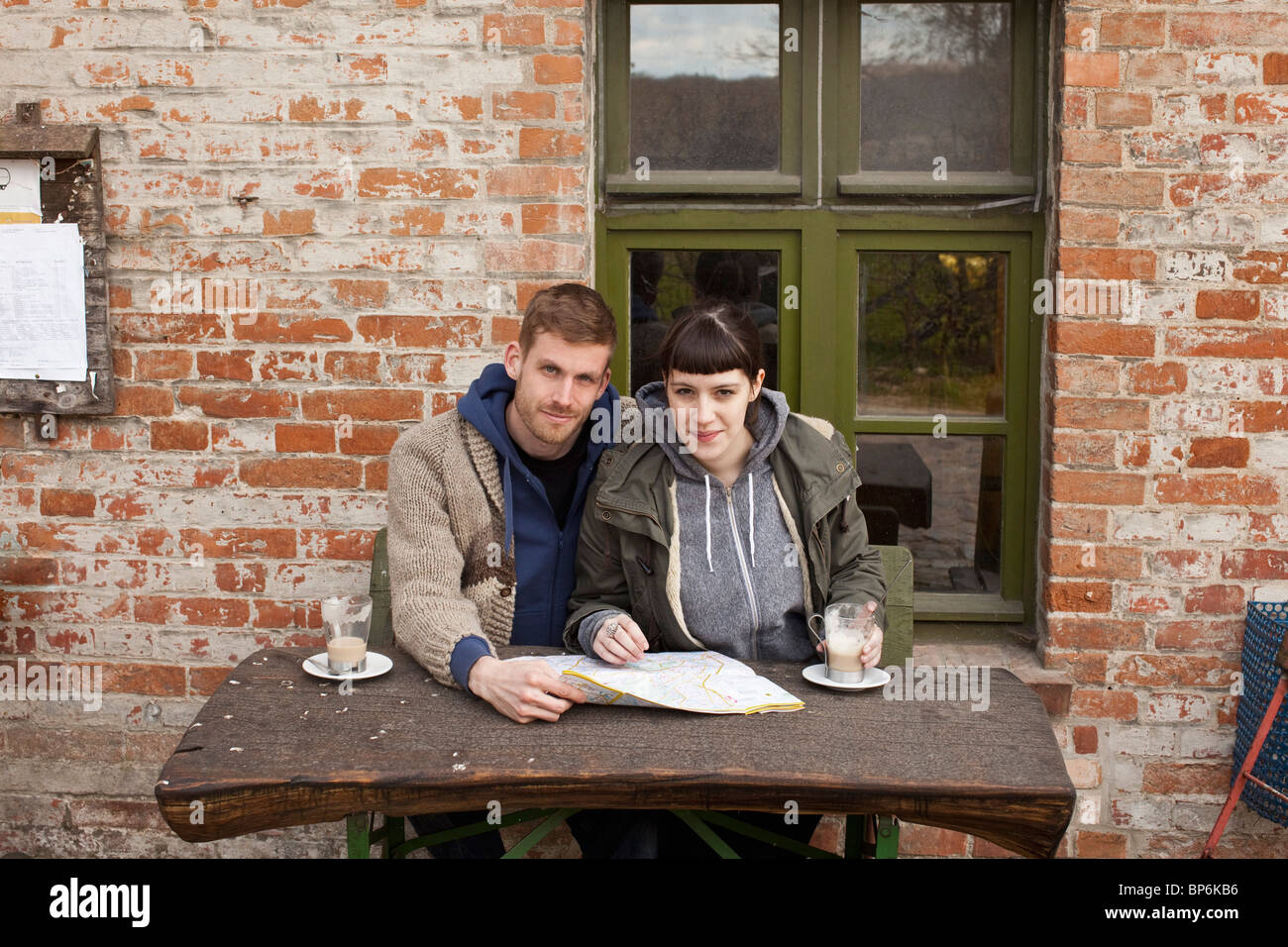 A couple with a map having lattes at an outdoor cafe Stock Photo - Alamy