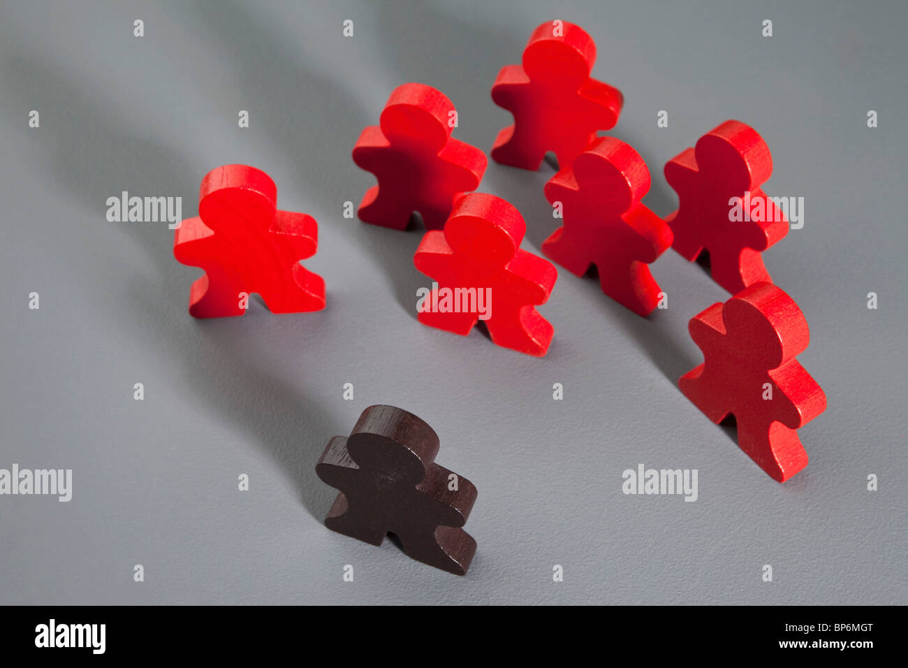 A group of red wooden stick figures confronting a brown wooden stick ...
