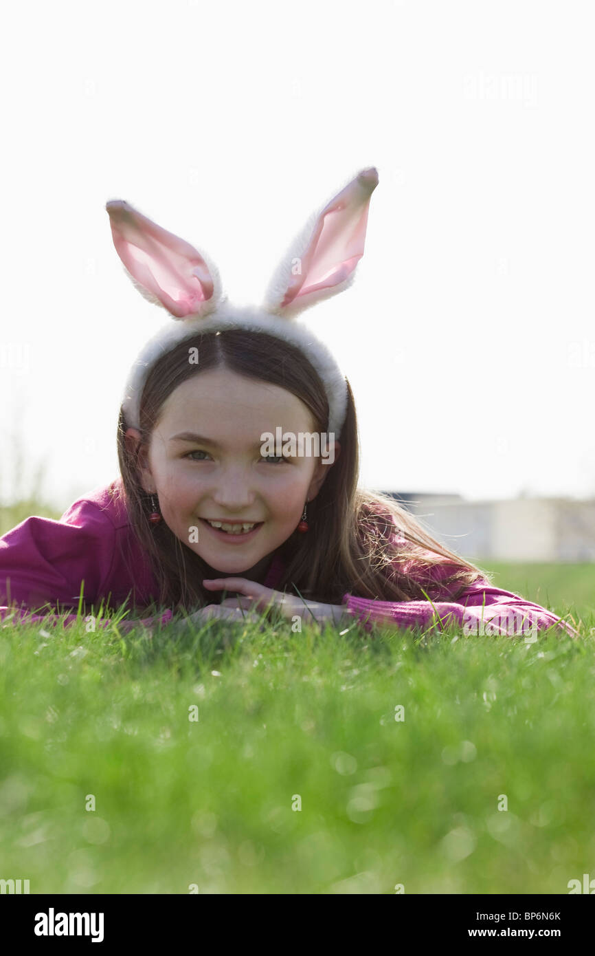 A girl wearing rabbit ears and lying down on grass Stock Photo - Alamy