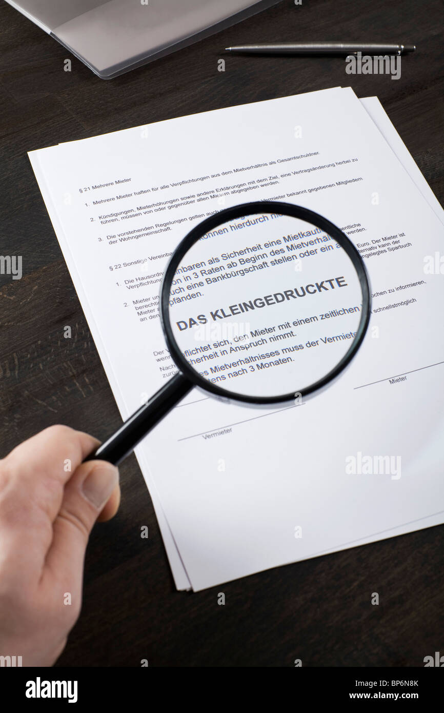 Examining the fine print of a German rental contract with a magnifying ...