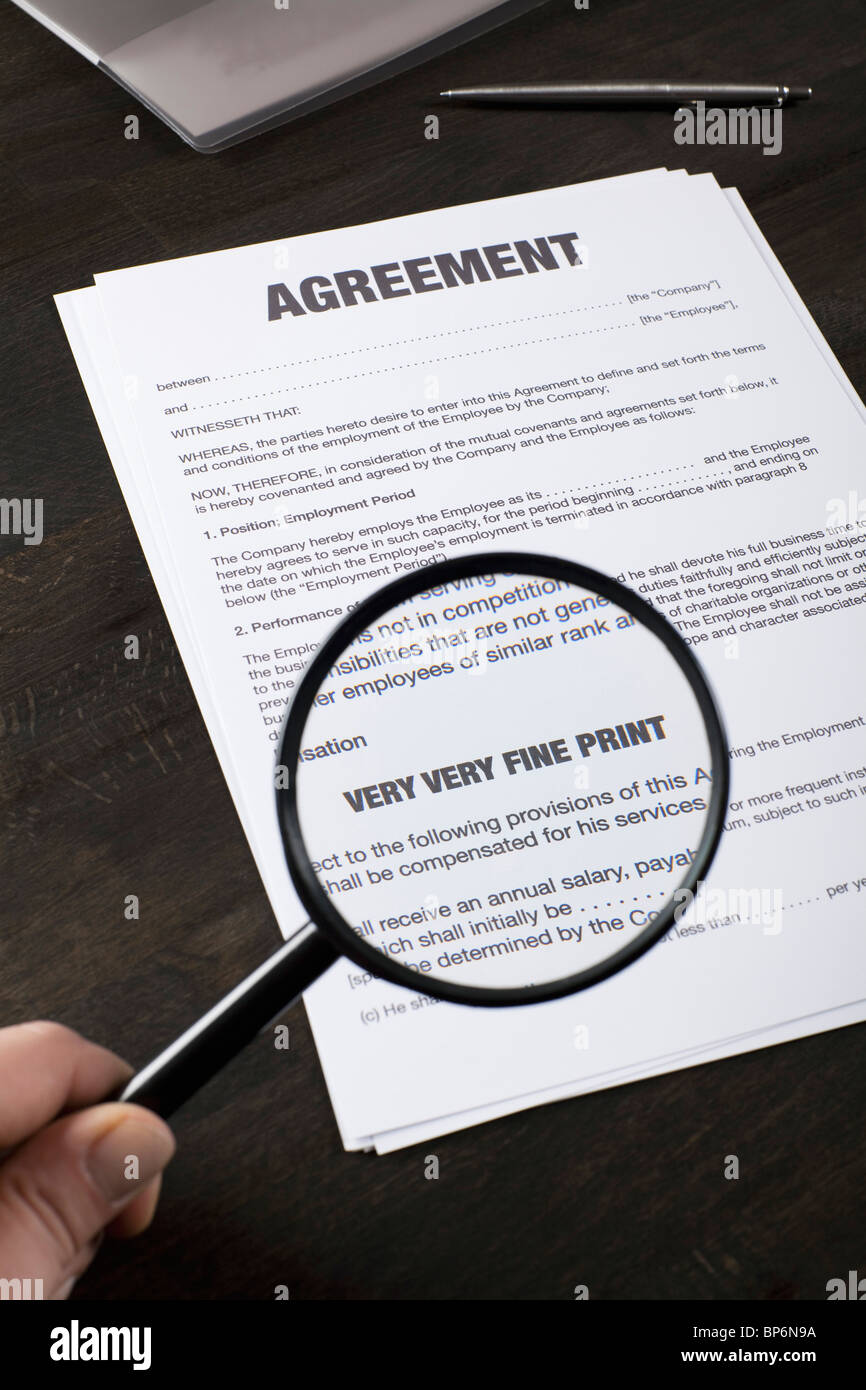 Examining the fine print of an employment agreement with a magnifying ...