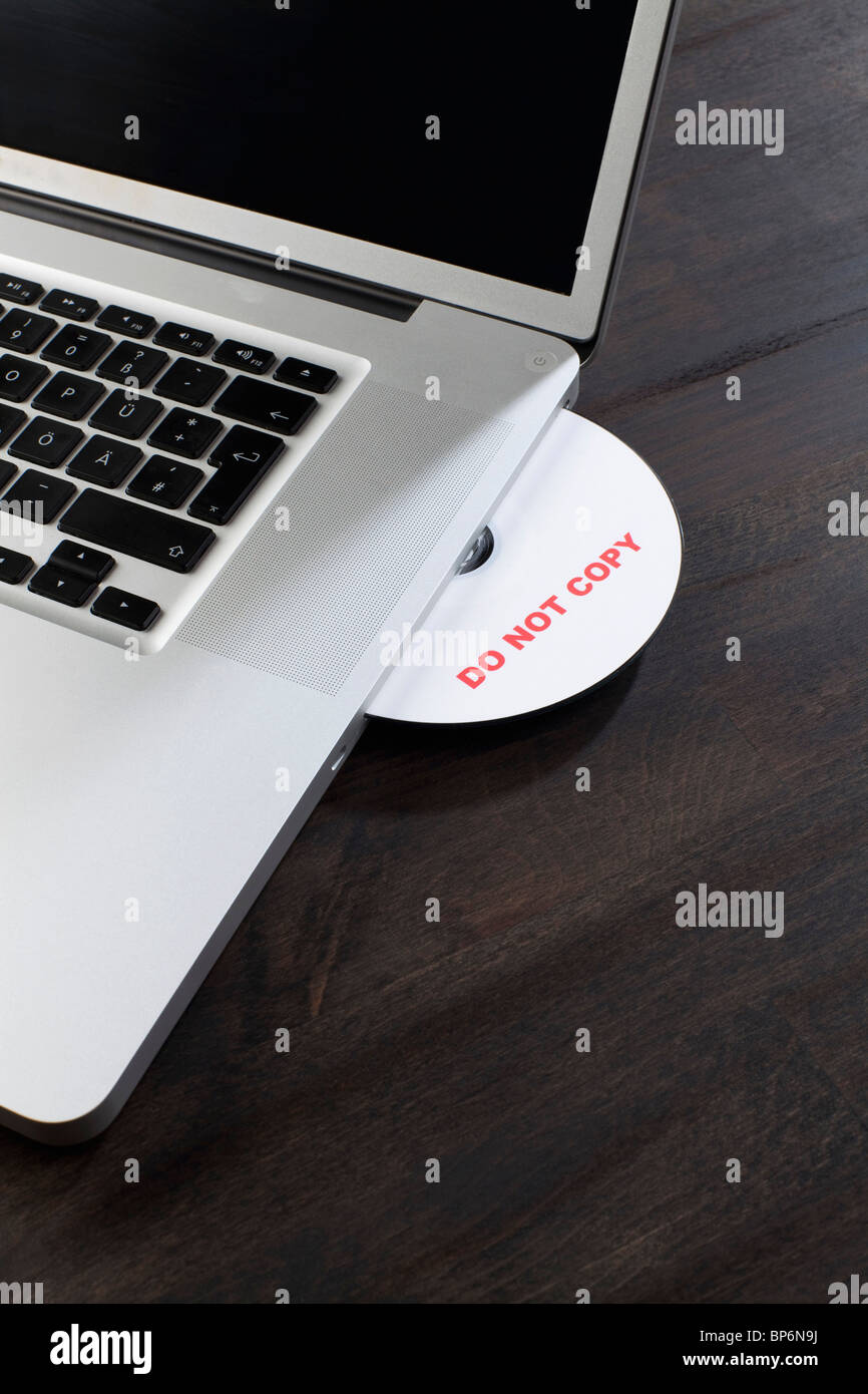 A disk with DO NOT COPY on it being inserted into a laptop Stock Photo ...