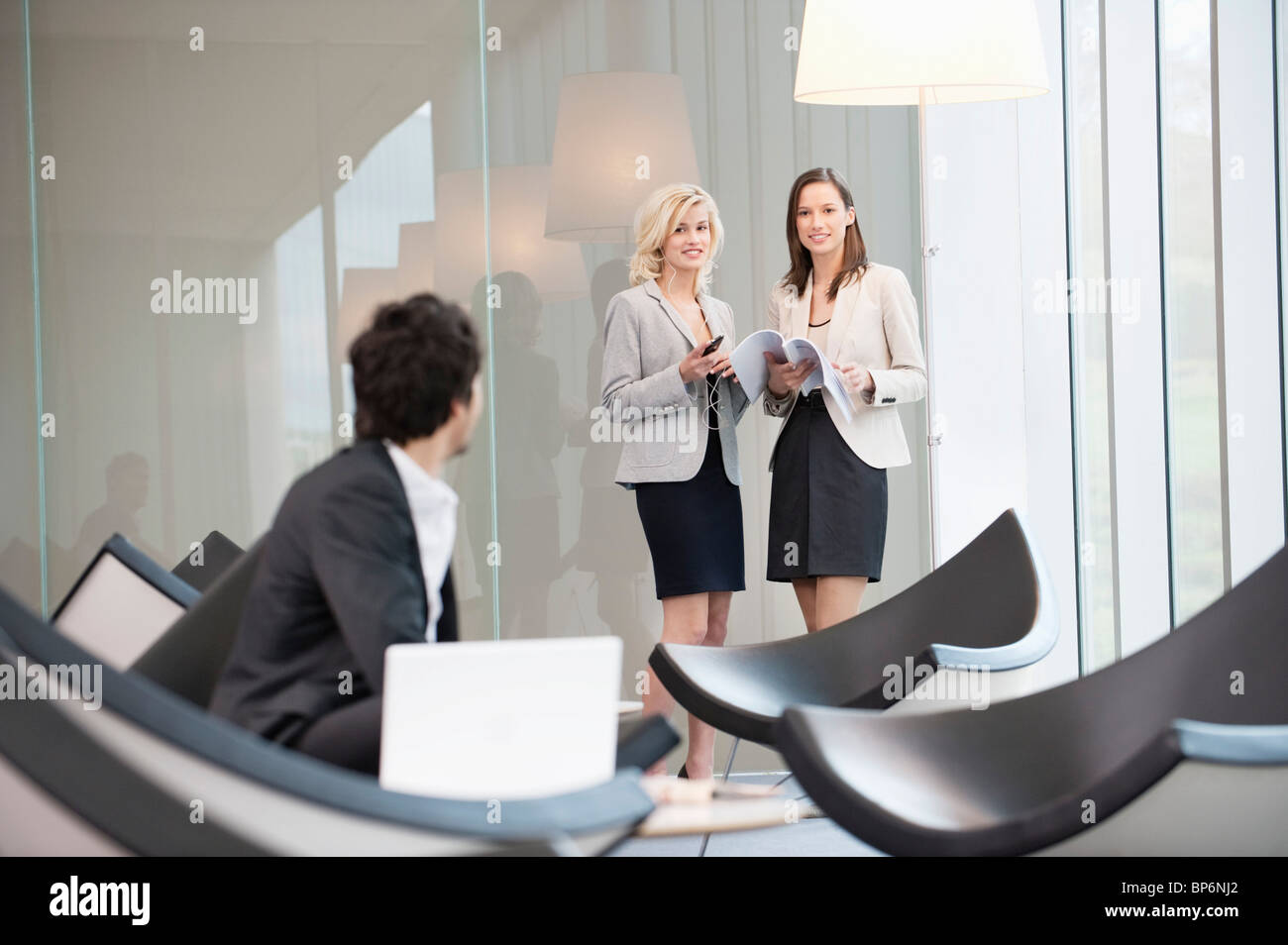 Businessman sitting in a waiting room looking at his colleagues ...