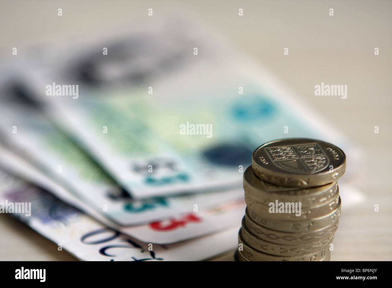 A stack of sterling £1 coins in front of different denomination ...