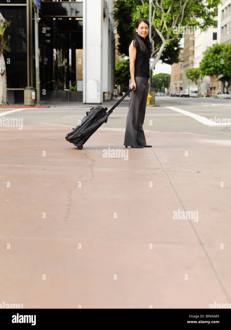 A businesswoman pulling a rolling suitcase Stock Photo - Alamy