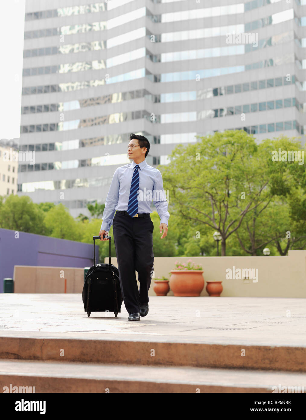 A businessman pulling a rolling suitcase Stock Photo - Alamy