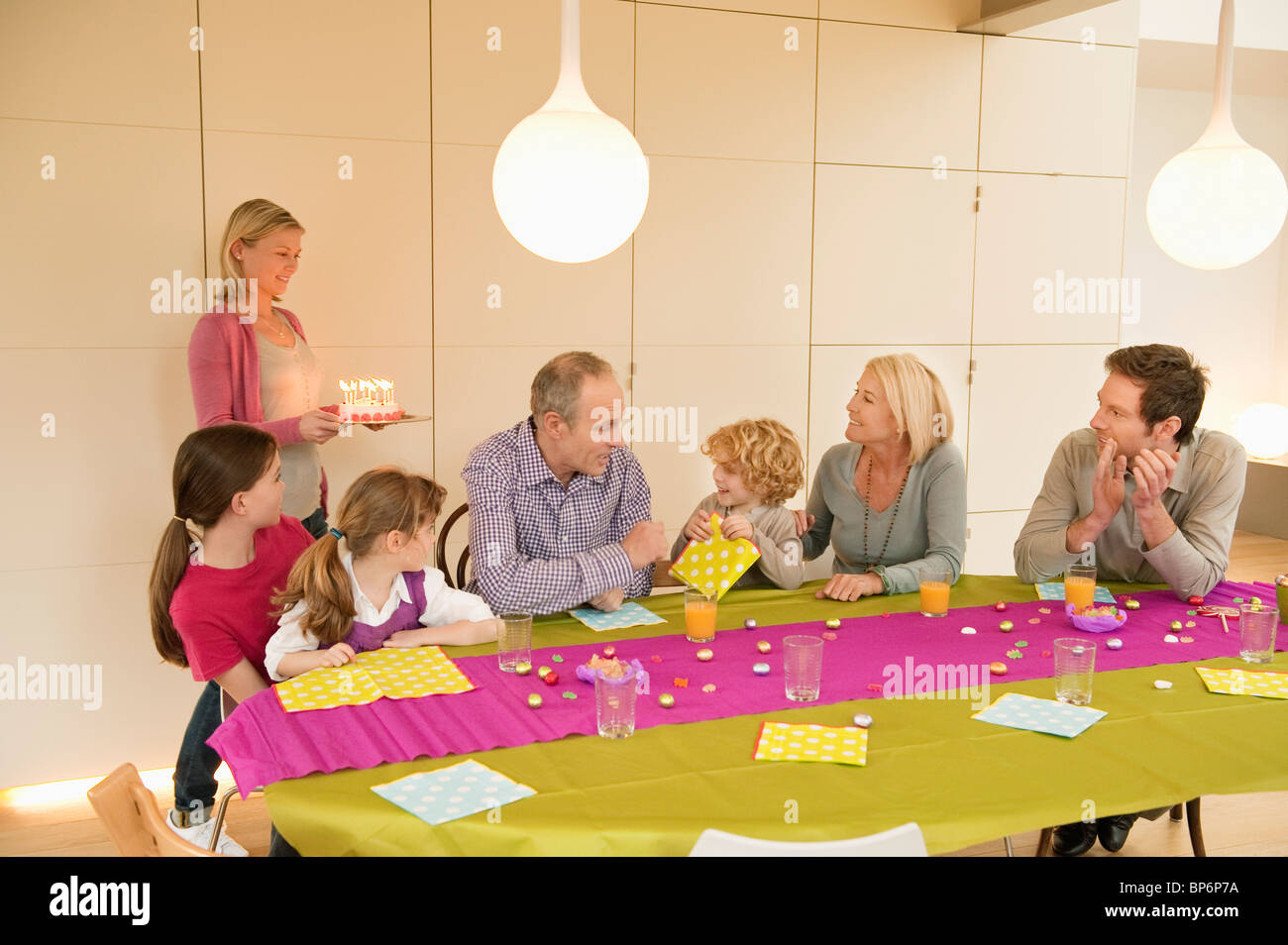 Family at a birthday celebration with a woman bringing cake in the ...