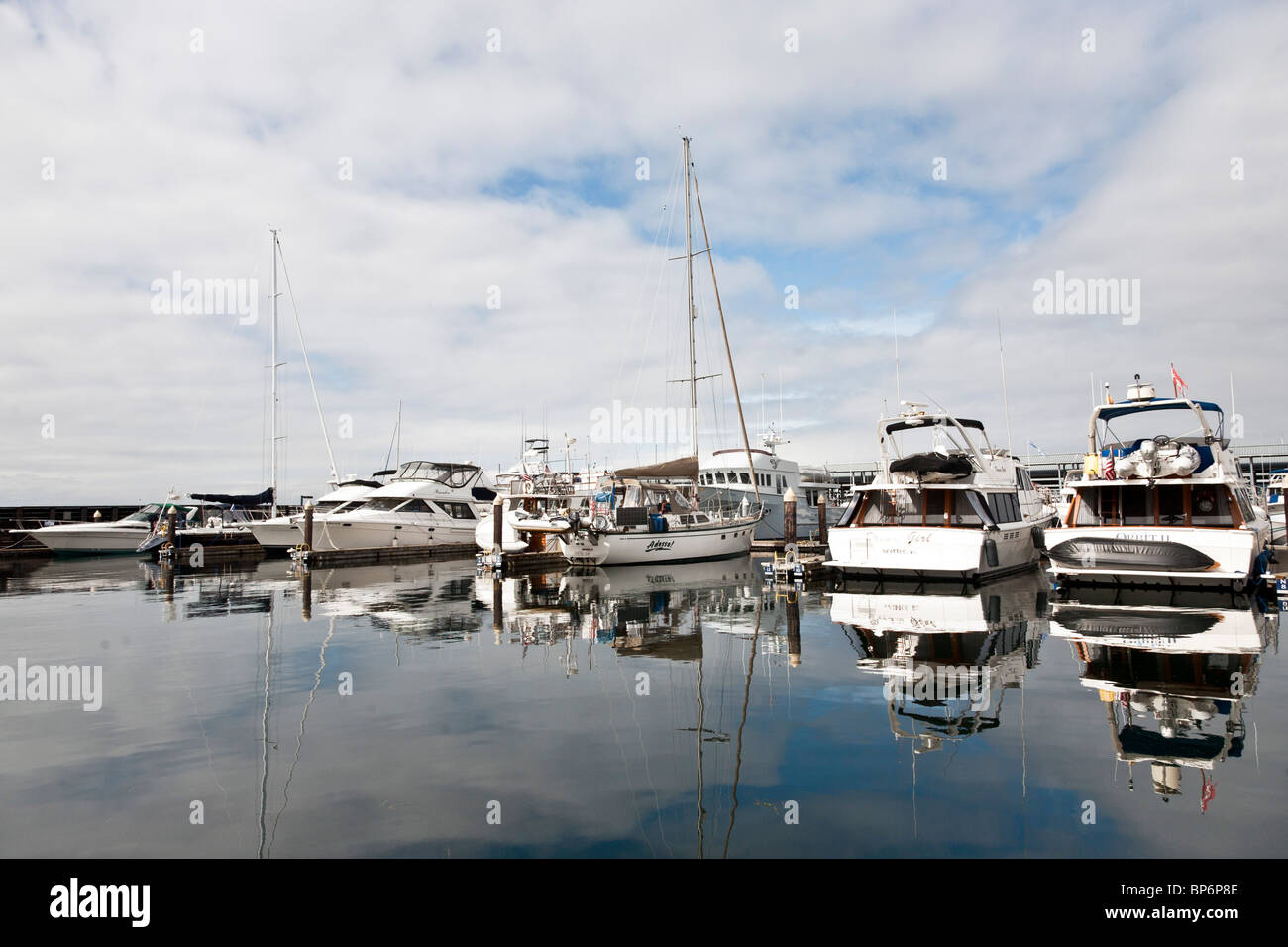 moored pleasure craft at rest & their reflections mirrored in still ...